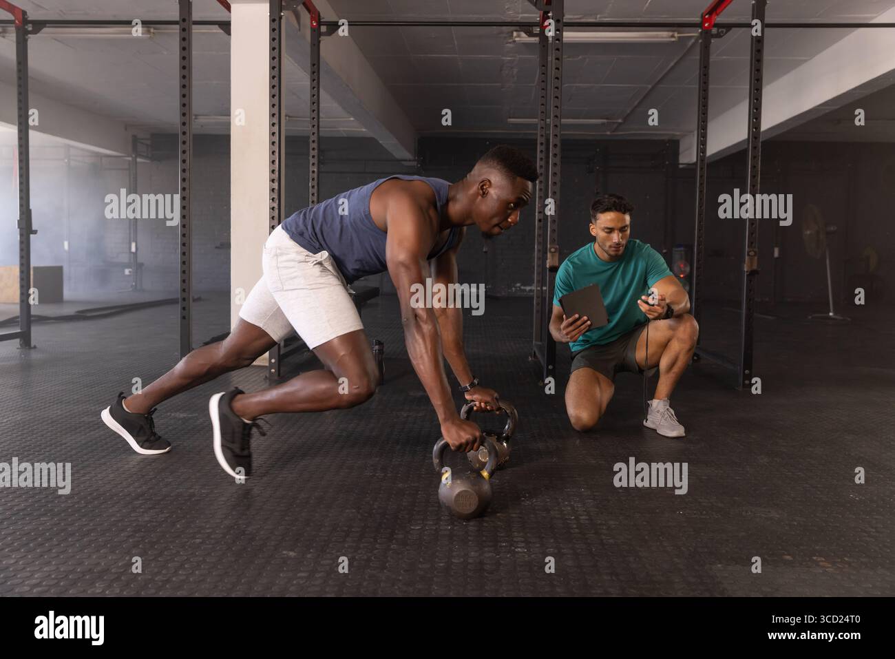 Male African American trainee, trainer guiding kettlebell climbers at ...