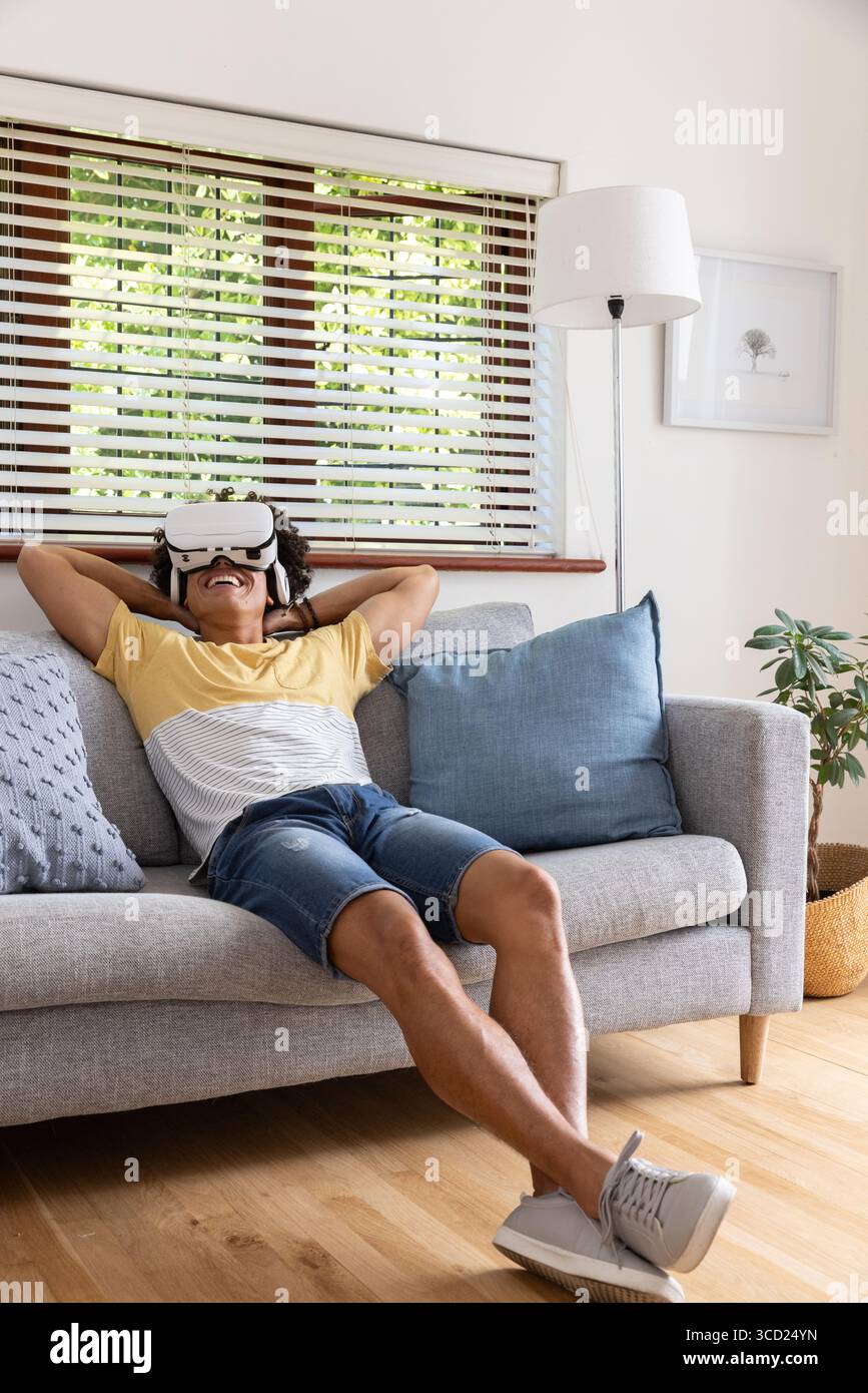 African American man reclining on gray sofa in living room wearing ...