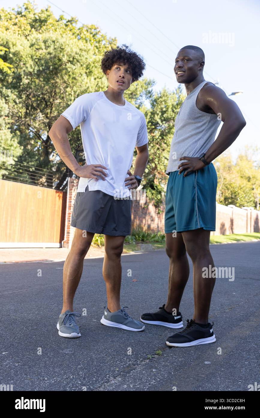 Diverse male friends standing and talking on suburban street with ...