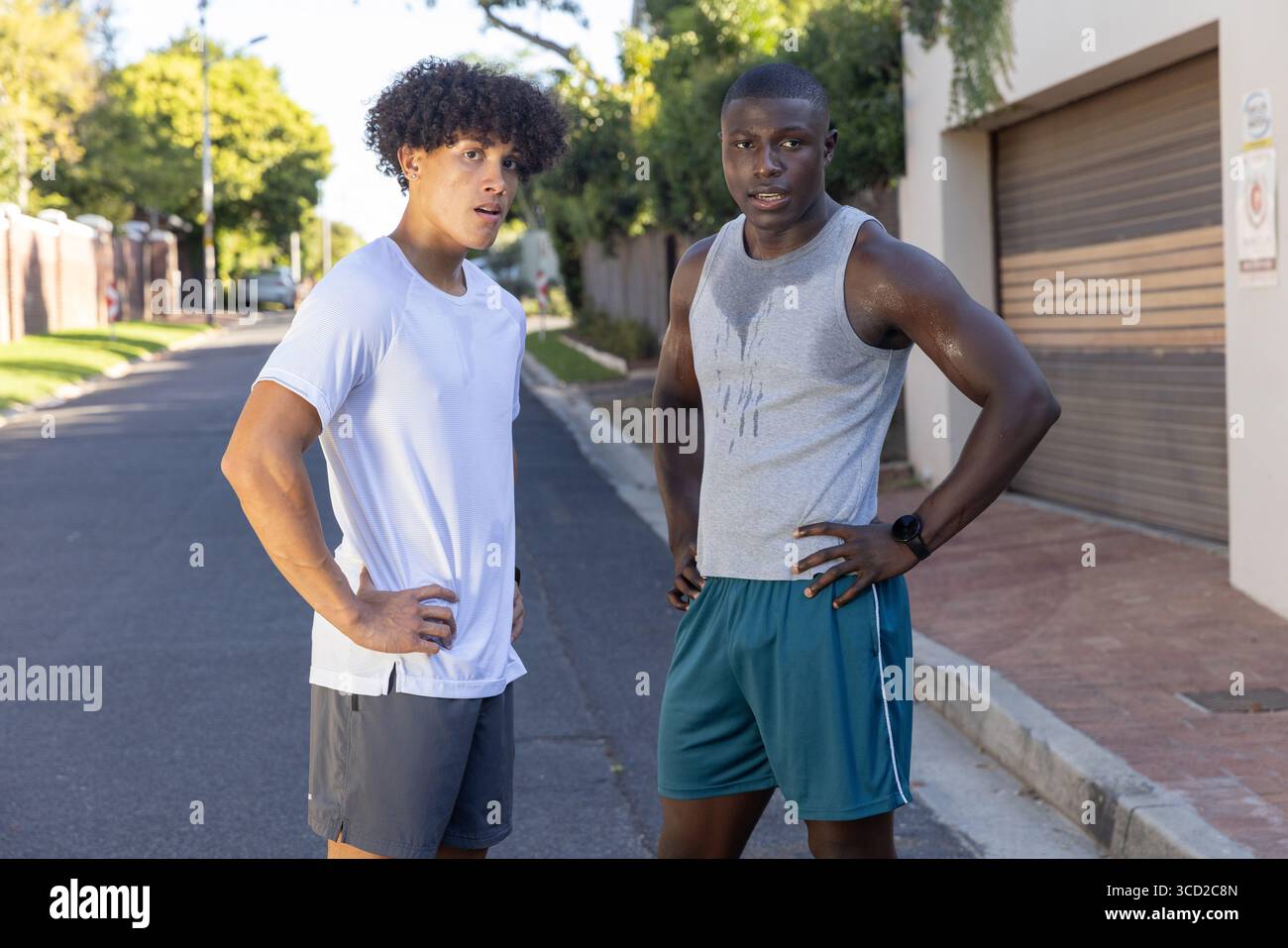 Diverse male friends standing and panting on suburban street with ...