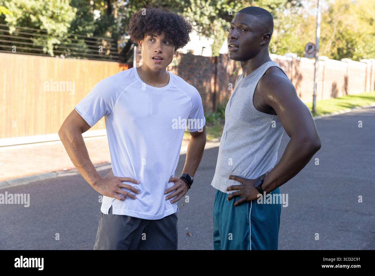 Diverse male friends standing and catching breath on suburban street ...