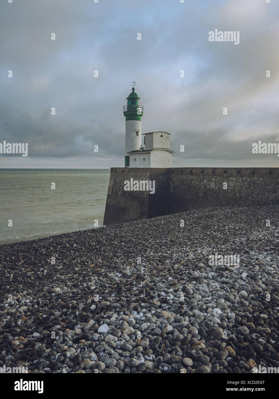 View of a lighthouse standing tall against the moody skies, its green ...