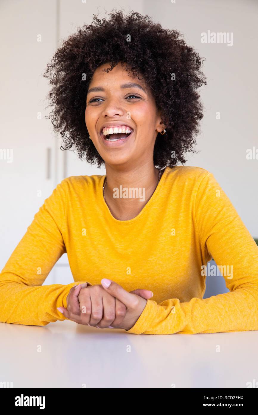 African American woman laughing at white table in kitchen with white ...