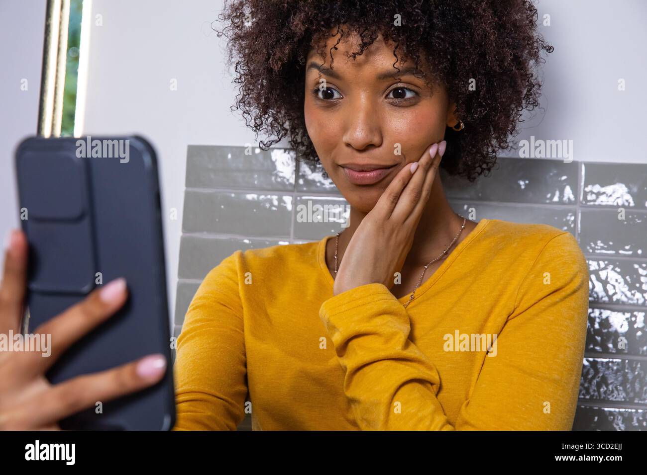 African American woman in mustard yellow top holding smartphone near ...