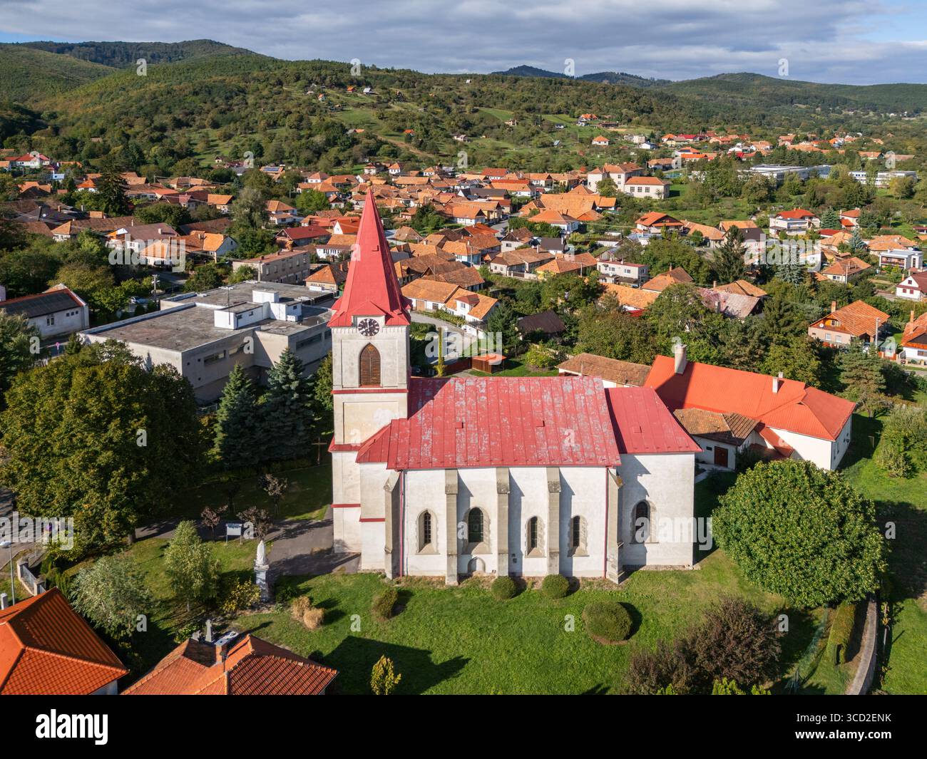 Aerial view of a church with a striking red roof stands prominently ...