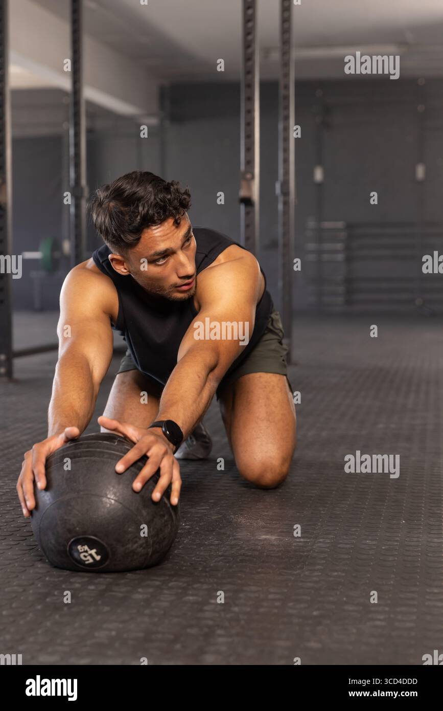 Male gymgoer kneeling in gym weight room near squat racks pushing 15 ...