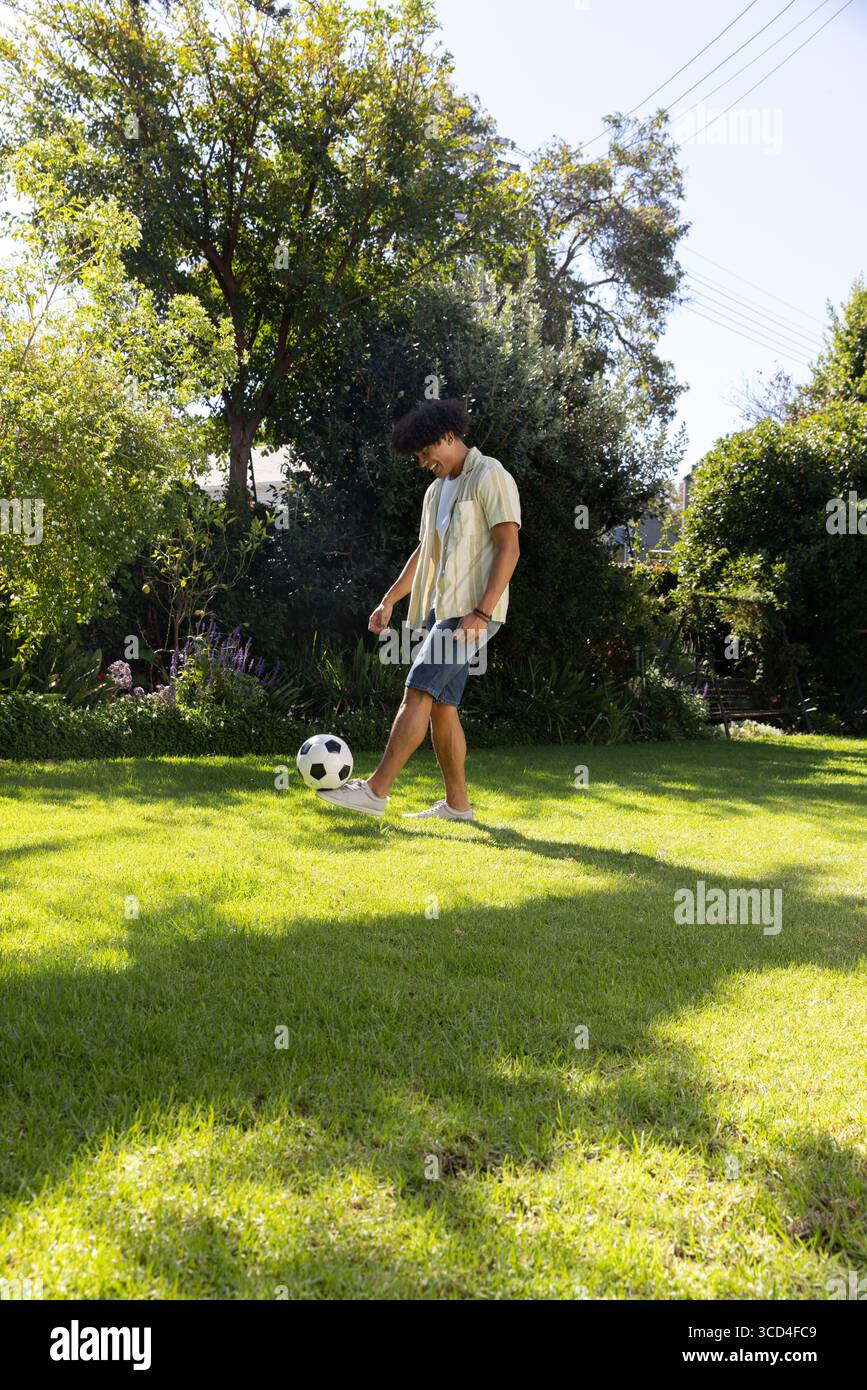 Man in twenties wearing shirt and shorts tapping soccer ball on ...