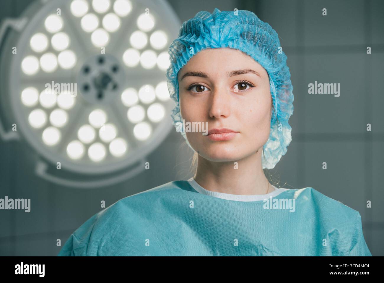 Female surgeon dressed in blue surgical attire, stands in a well-lit ...