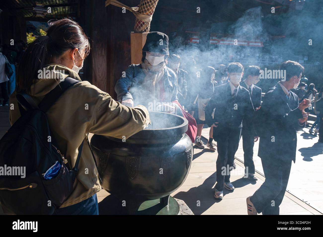 Woman placing burning incense in large bowl at the main hall of ...