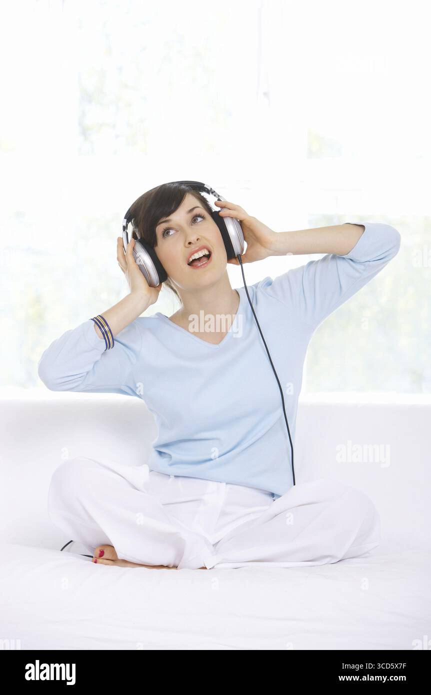 Woman Wearing Headphones and Singing while Sitting Cross Legged on the ...