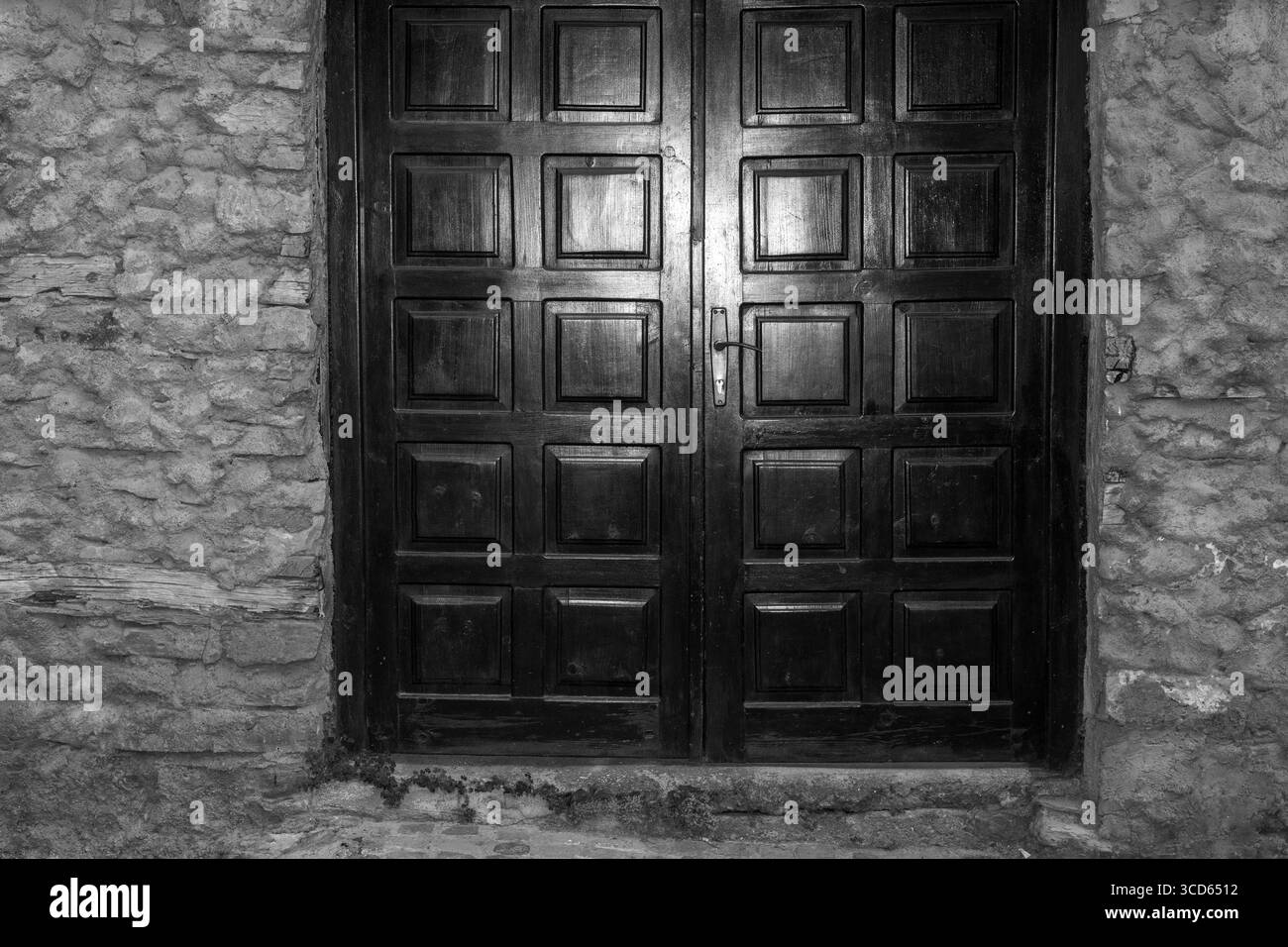 Illuminated Wooden Door with Square Patterns and Stone wall as ...