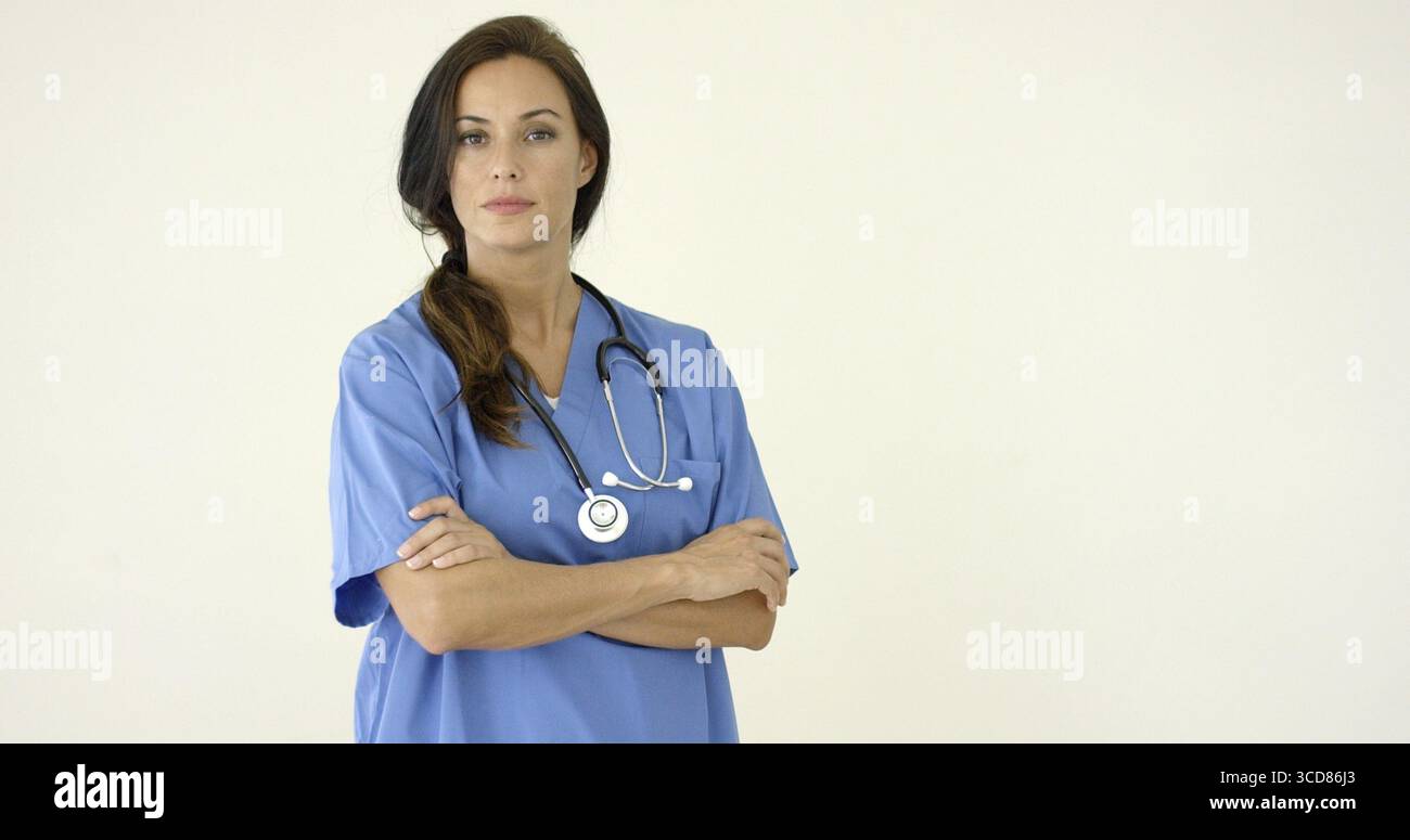 Woman in scrubs crosses arms and smiles at camera with stethoscope ...