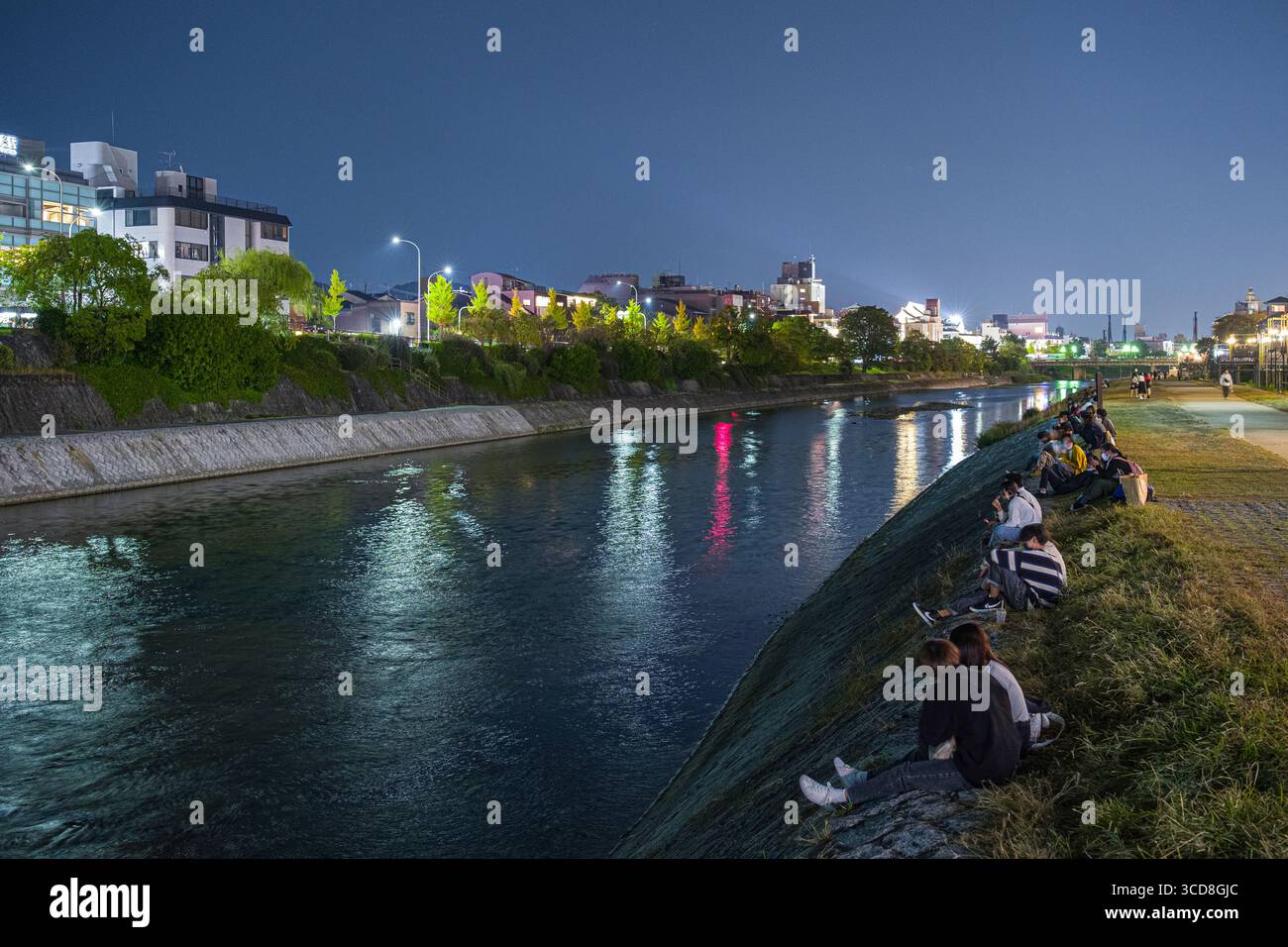 People sitting on the west bank of the Kamogawa River at night ...