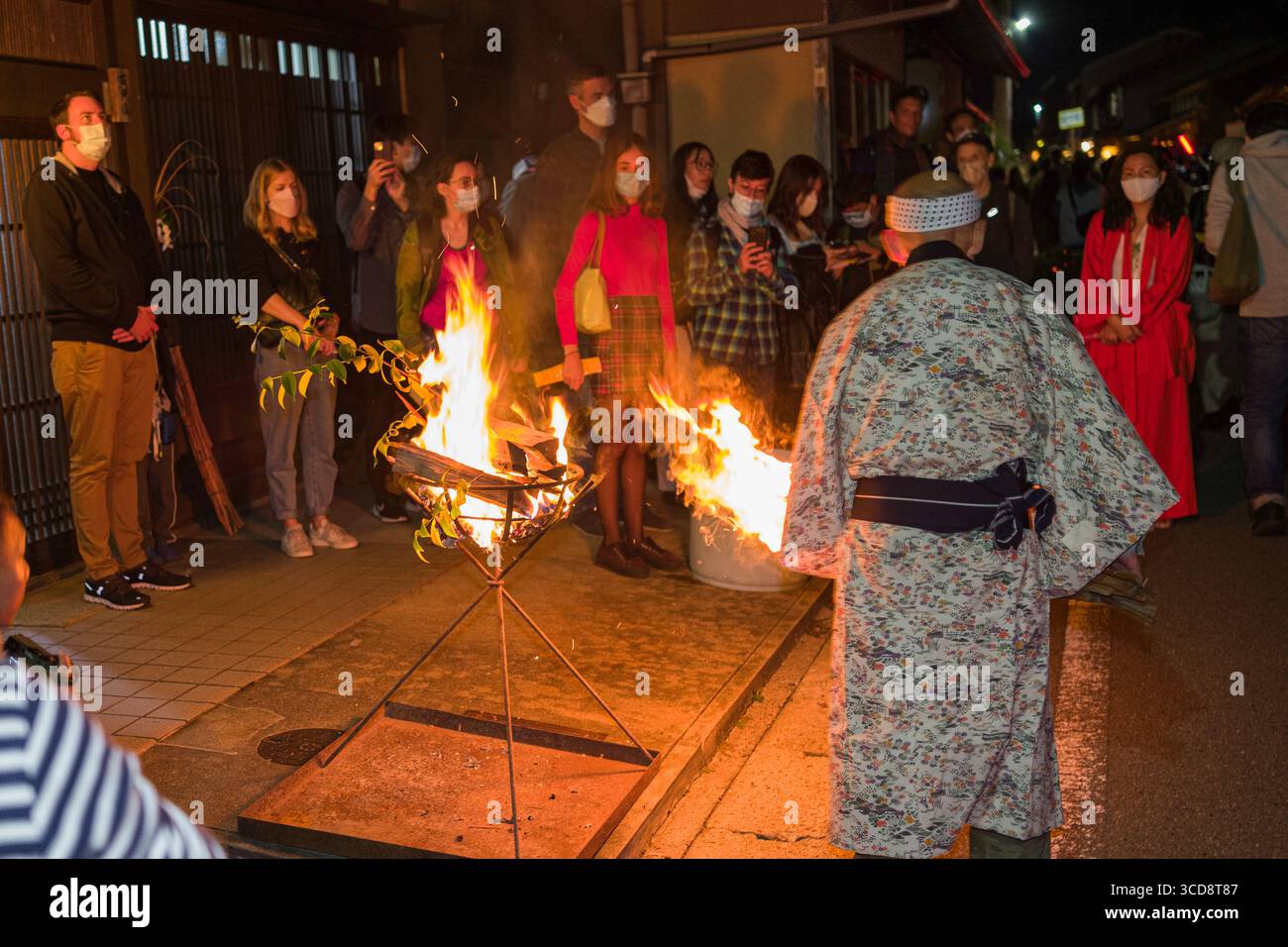 Man using a torch to light small fires in elevated fire grate in front ...