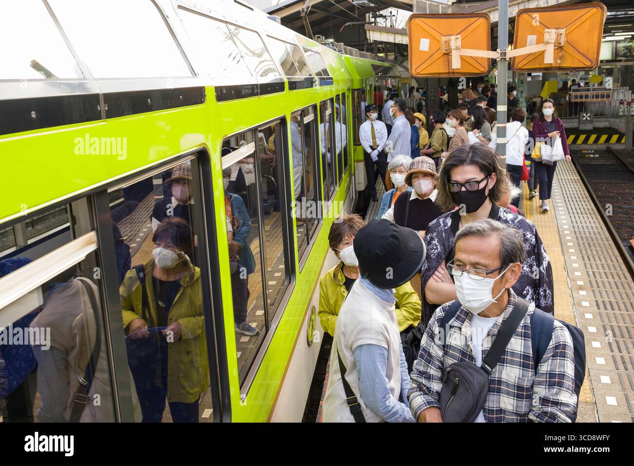 Line of passengers waiting to board an Eiden 901 train at Demachiyanagi ...