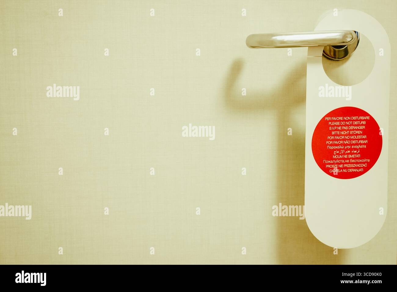 A “Do Not Disturb” card hanging on a hotel door with a white background ...