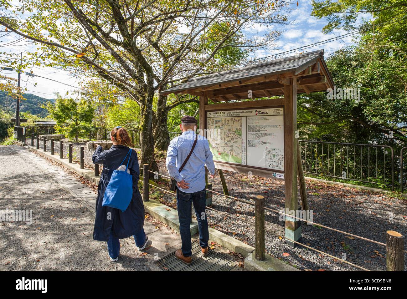 Woman and man looking at local sightseeing guide map posted in a wooden ...