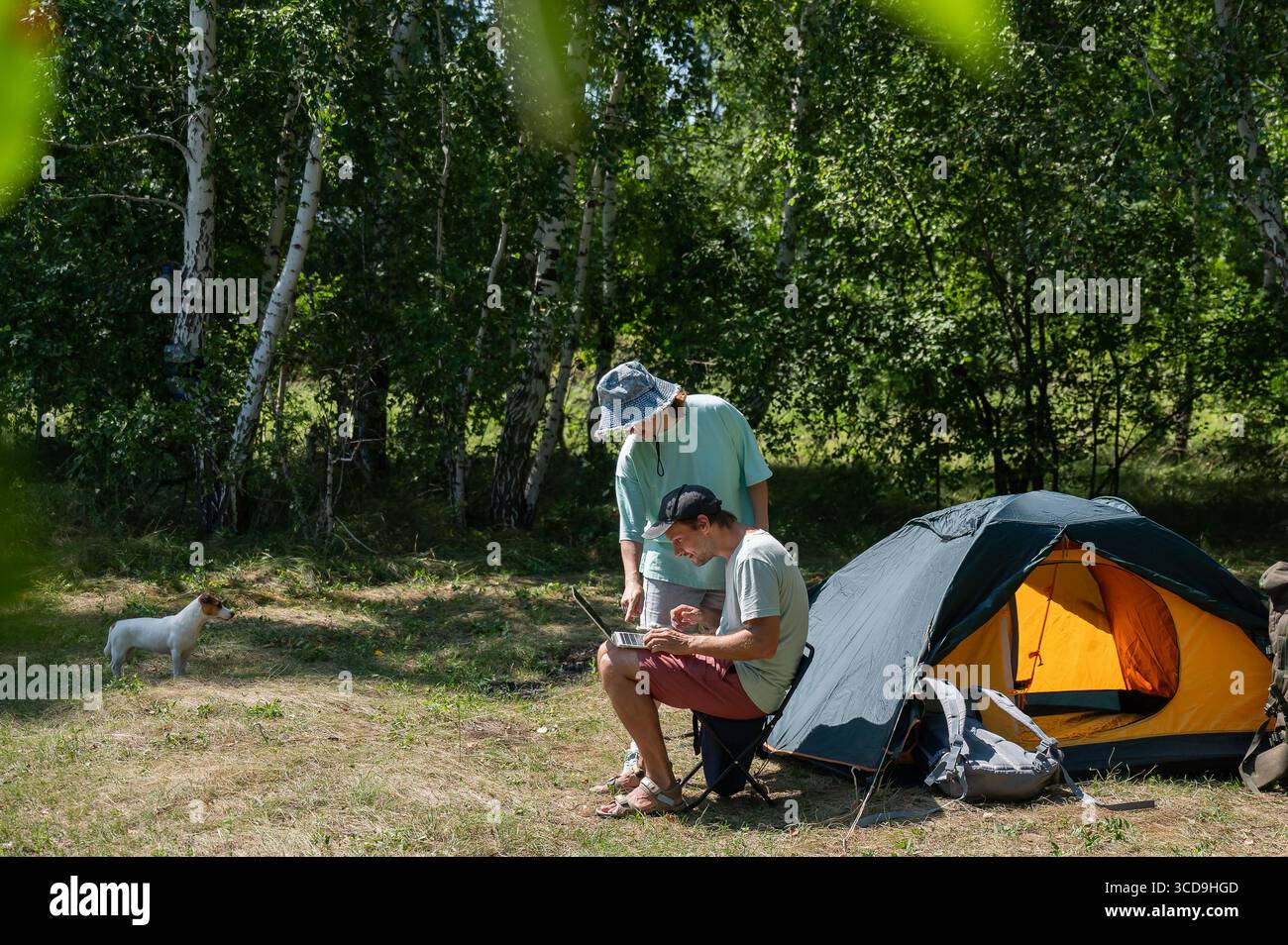 Caucasian man working on laptop in camping. Couple relaxing in nature ...