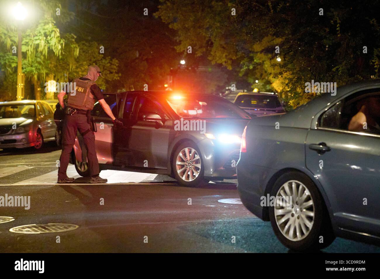 A masked FBI agent gets back into an unmarked vehicle after agents from ...