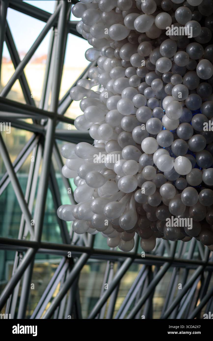 Cluster of white balloons suspended in a modern architectural space ...