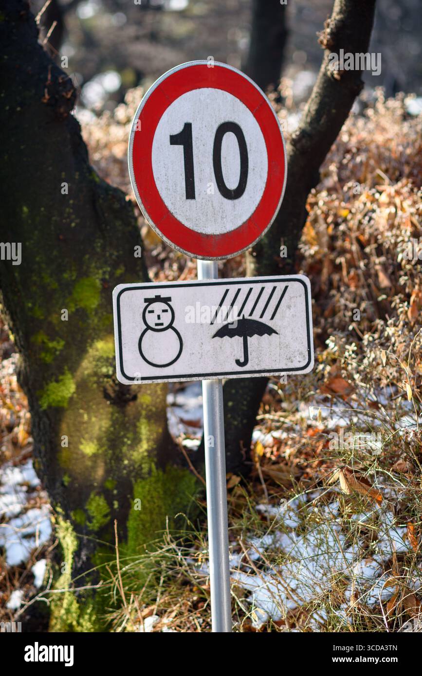 A speed limit sign with a snowman and umbrella symbol cautioning slower ...