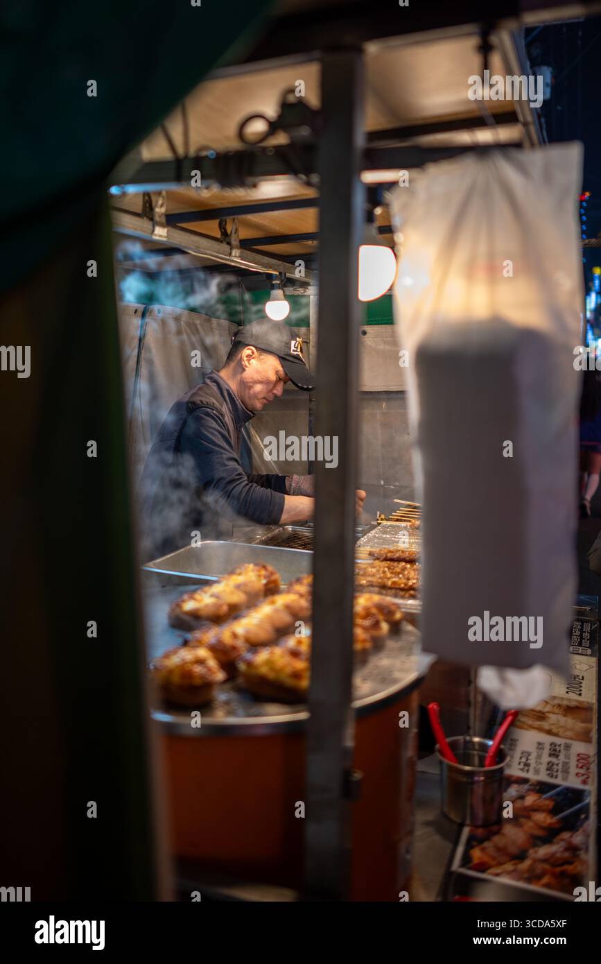 Street vendor cooking skewered food at a night market in Hongdae ...