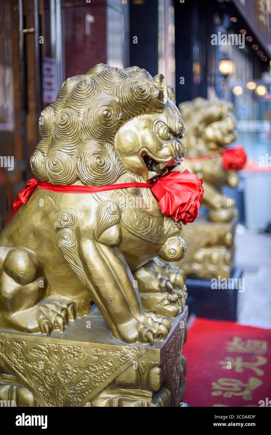 Golden Chinese guardian lion statues with red ribbons at the entrance ...