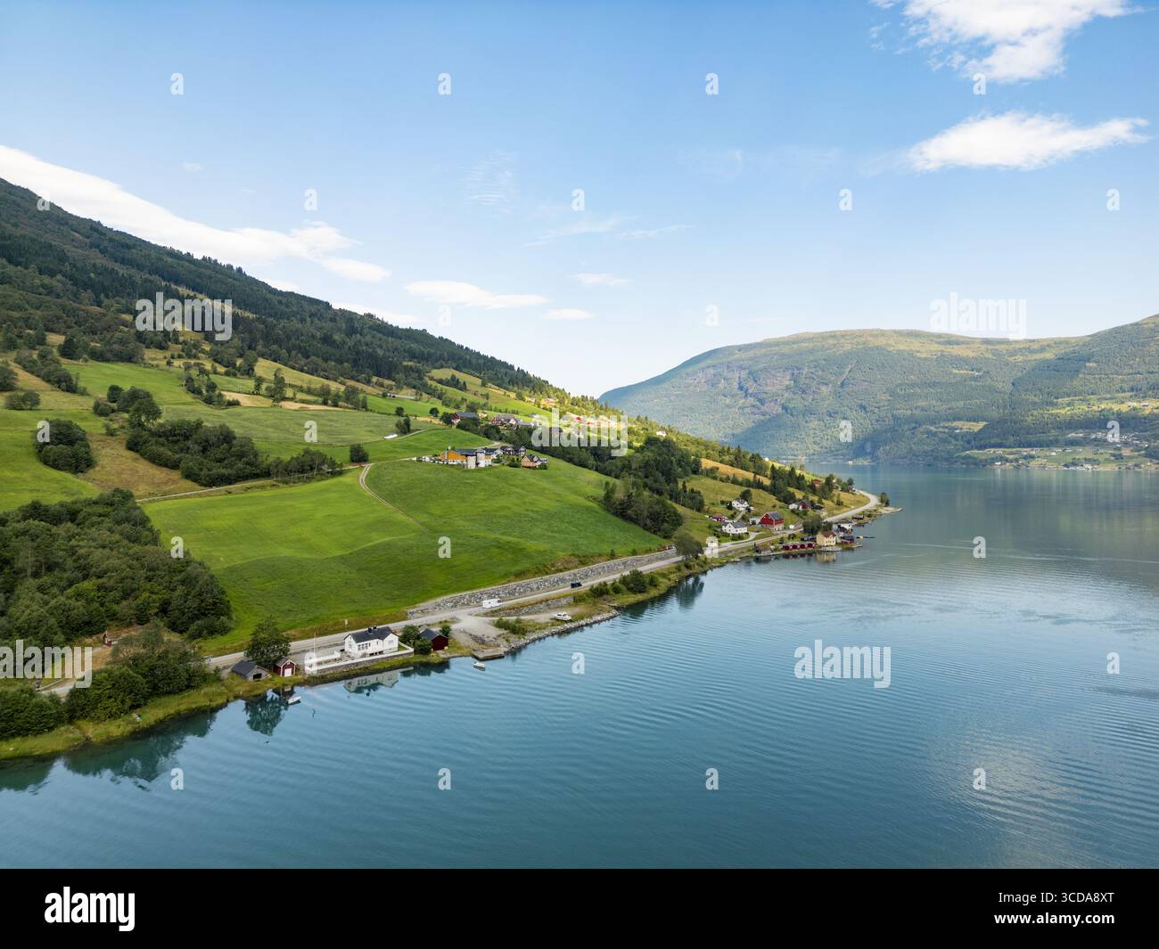 Aerial view of verdant hillsides meet the tranquil fjord under a vast ...
