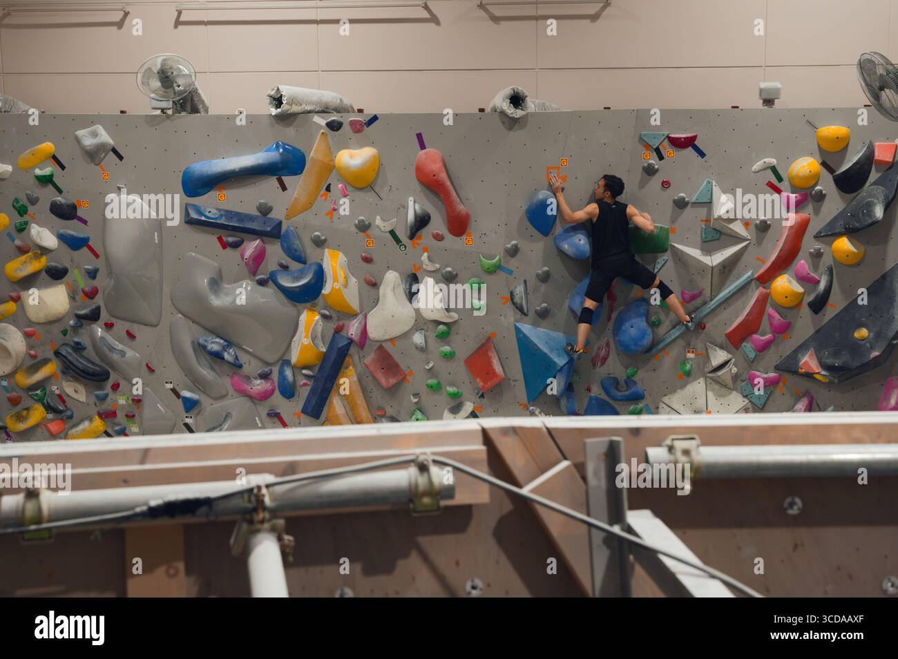 Indoor bouldering athlete scaling a colorful climbing wall with dynamic ...