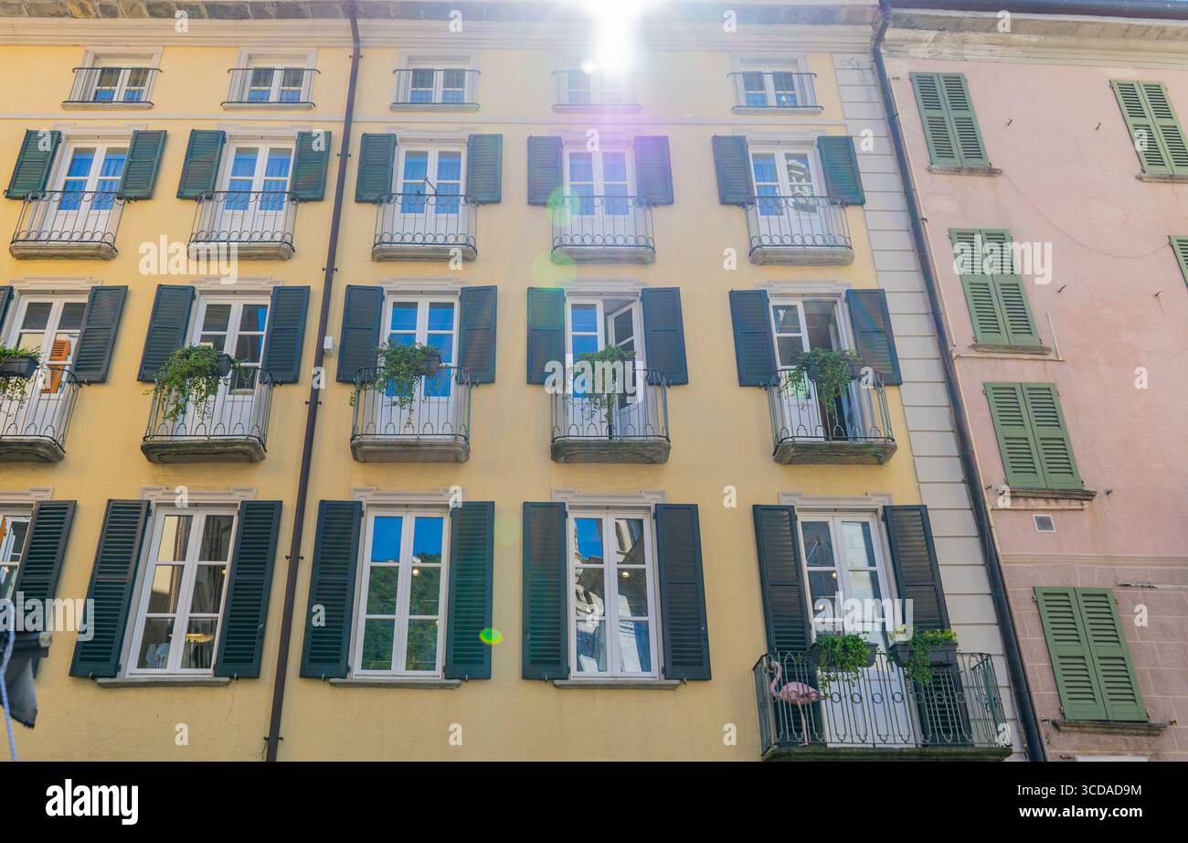 Windows with wooden shutters. Small balcony with flowers in summer ...