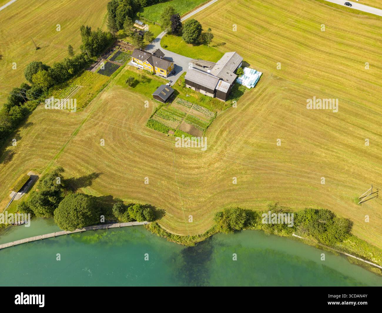 Aerial view of the golden fields meet the emerald waters of Stryn river ...