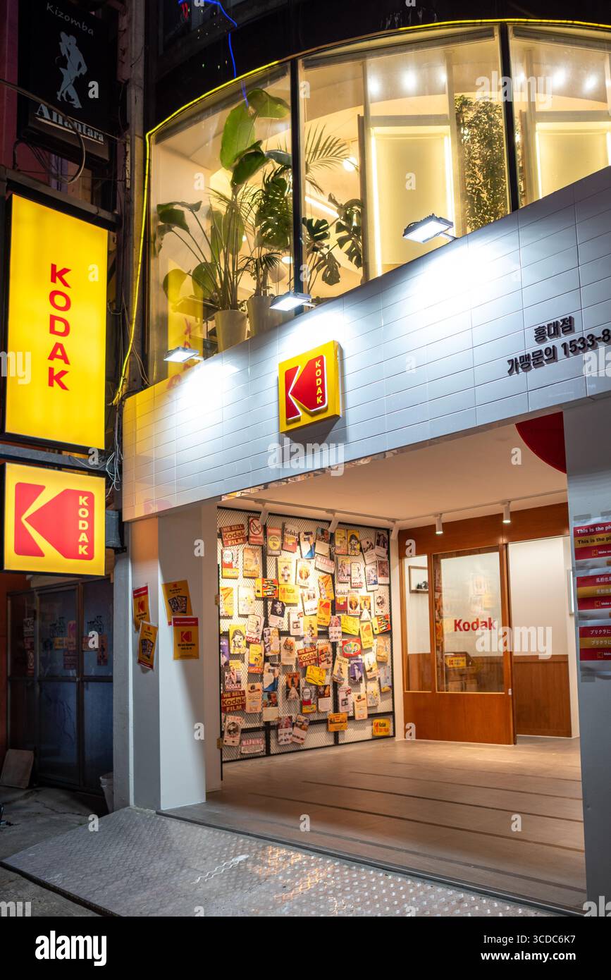 A brightly lit kodak store at night with neon signs, showcasing various ...