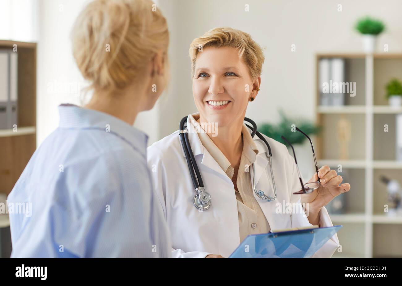 Female doctor consulting young adult patient in clinic Stock Photo - Alamy