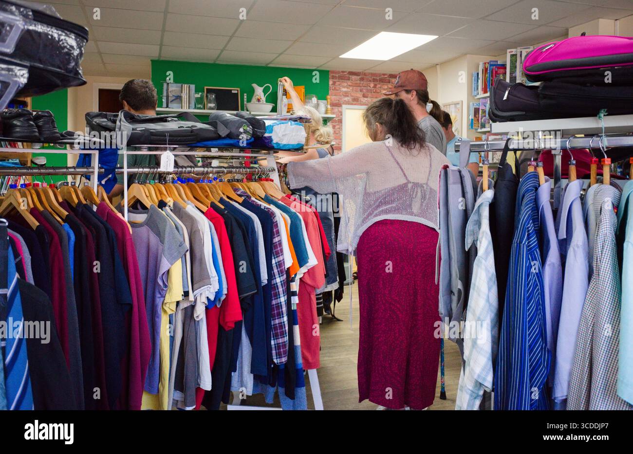 People looking at shirts in a charity shop Stock Photo - Alamy