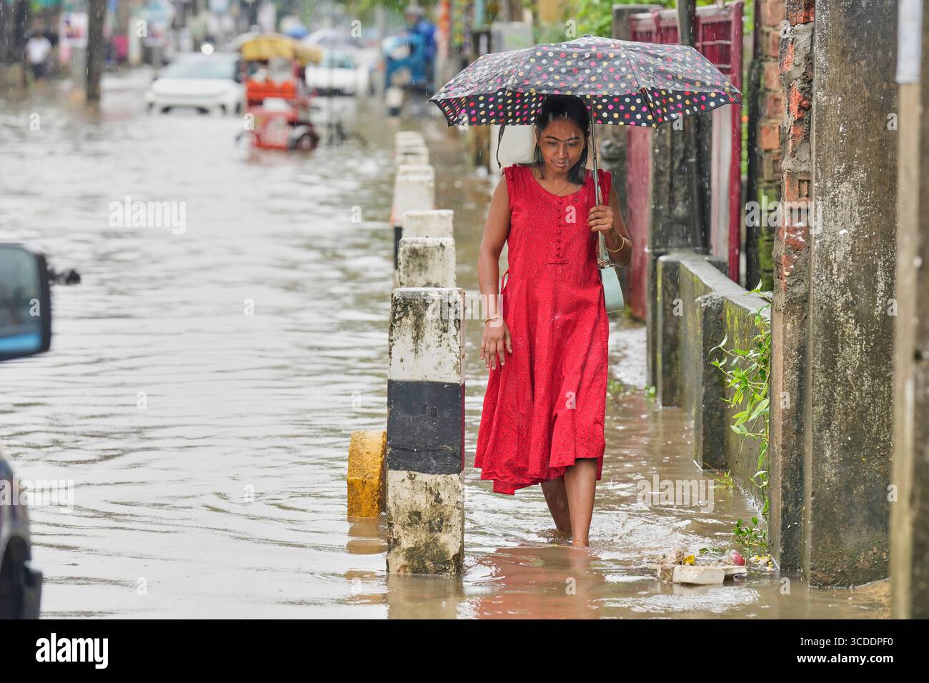 A woman wades through a flooded street after heavy monsoon rain in Guwahati, Wednesday, Aug. 13 ...