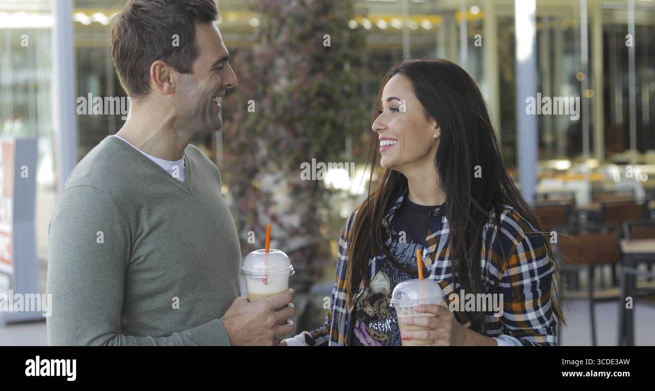 Happy relaxed young couple enjoying takeaway coffee standing together ...