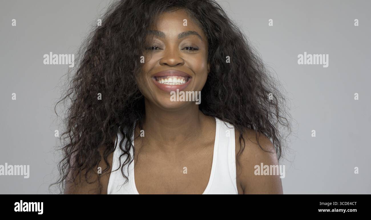 Delighted ethnic female in white top laughing at joke and looking at ...