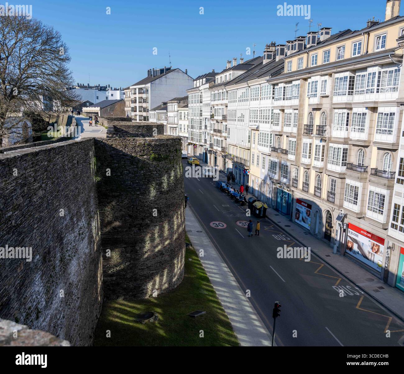 Ancient stone wall of Lugo, Spain alongside a modern city street with ...