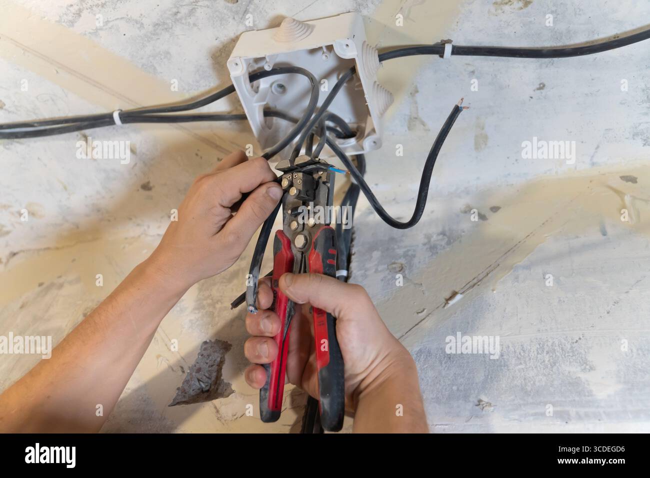 Electrician uses pliers to meticulously cut and prepare electrical ...
