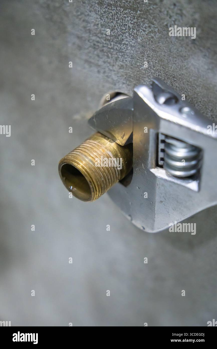 Close-up of plumber tightening brass pipe fitting using adjustable ...