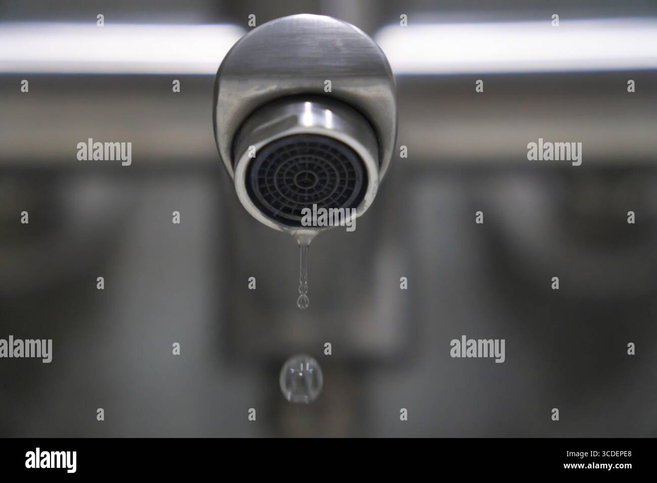 Close-up view of a dripping faucet in a modern bathroom, emphasizing ...