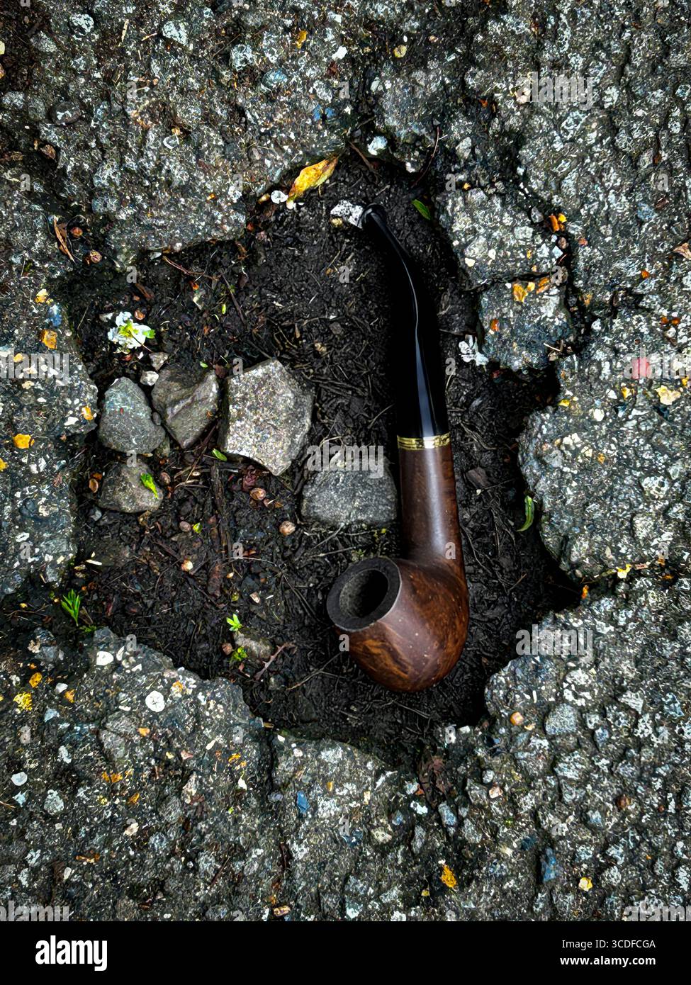Worn pothole in an asphalt covered section of road with a discarded old ...