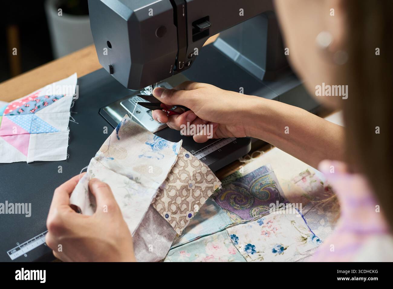Young adult Caucasian woman sewing fabric pieces with sewing machine ...