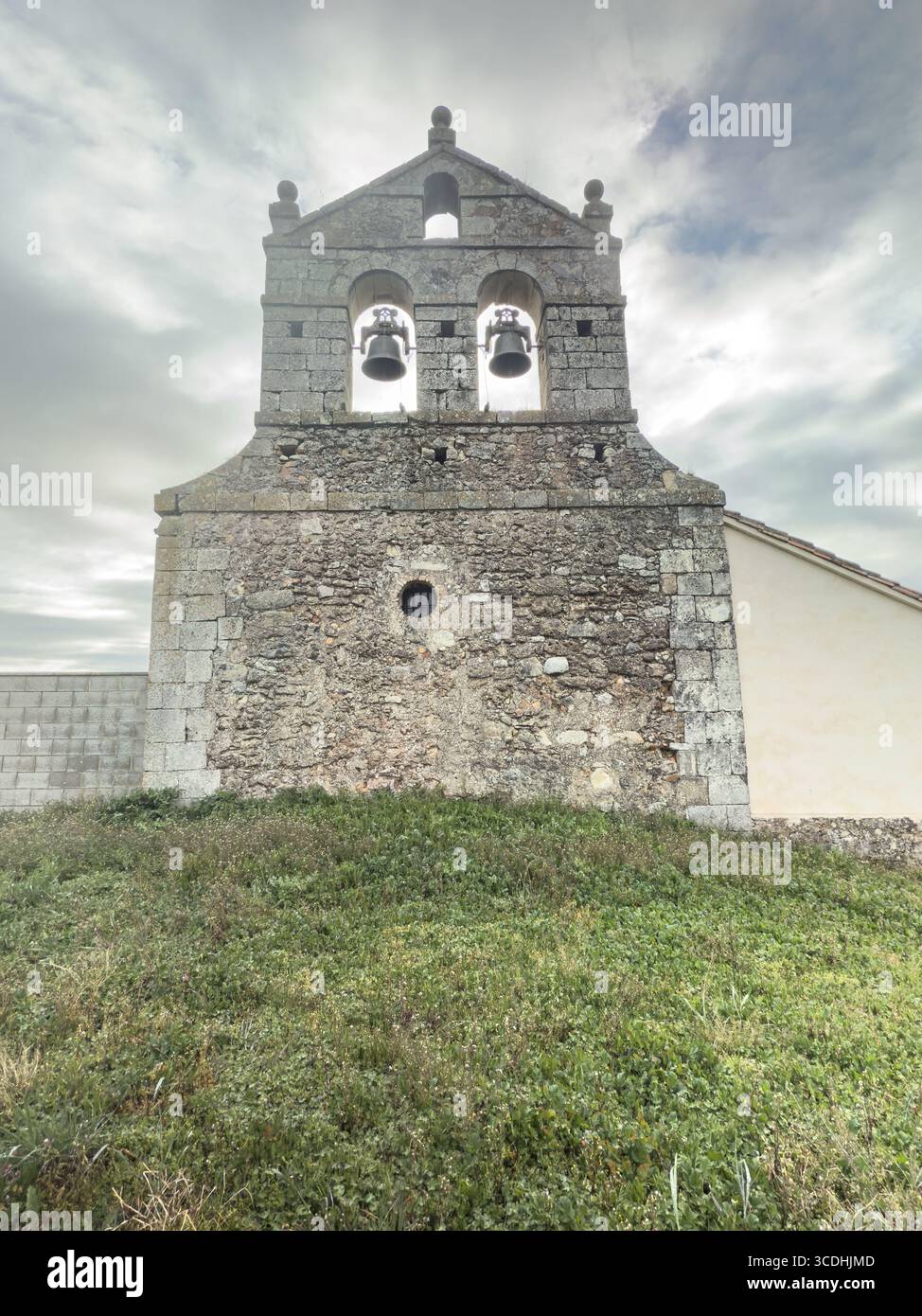 Ancient Romanesque stone bell gable with two bells on a grassy hill ...
