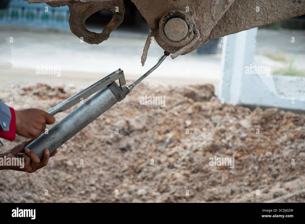 A mechanic is adding grease to a hydraulic cylinder of a machine Stock ...