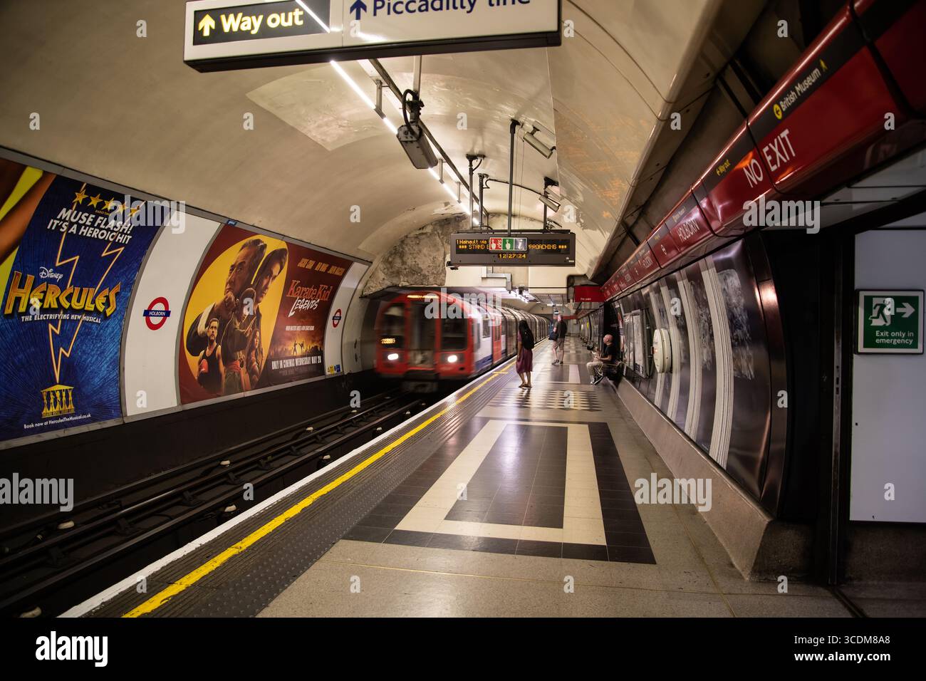 Central Line platform at Holborn Underground Station, London, with a red Tube train approaching ...