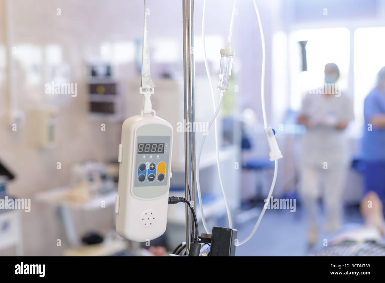 Close up infusion pump and IV line on a pole in a bright hospital ward ...