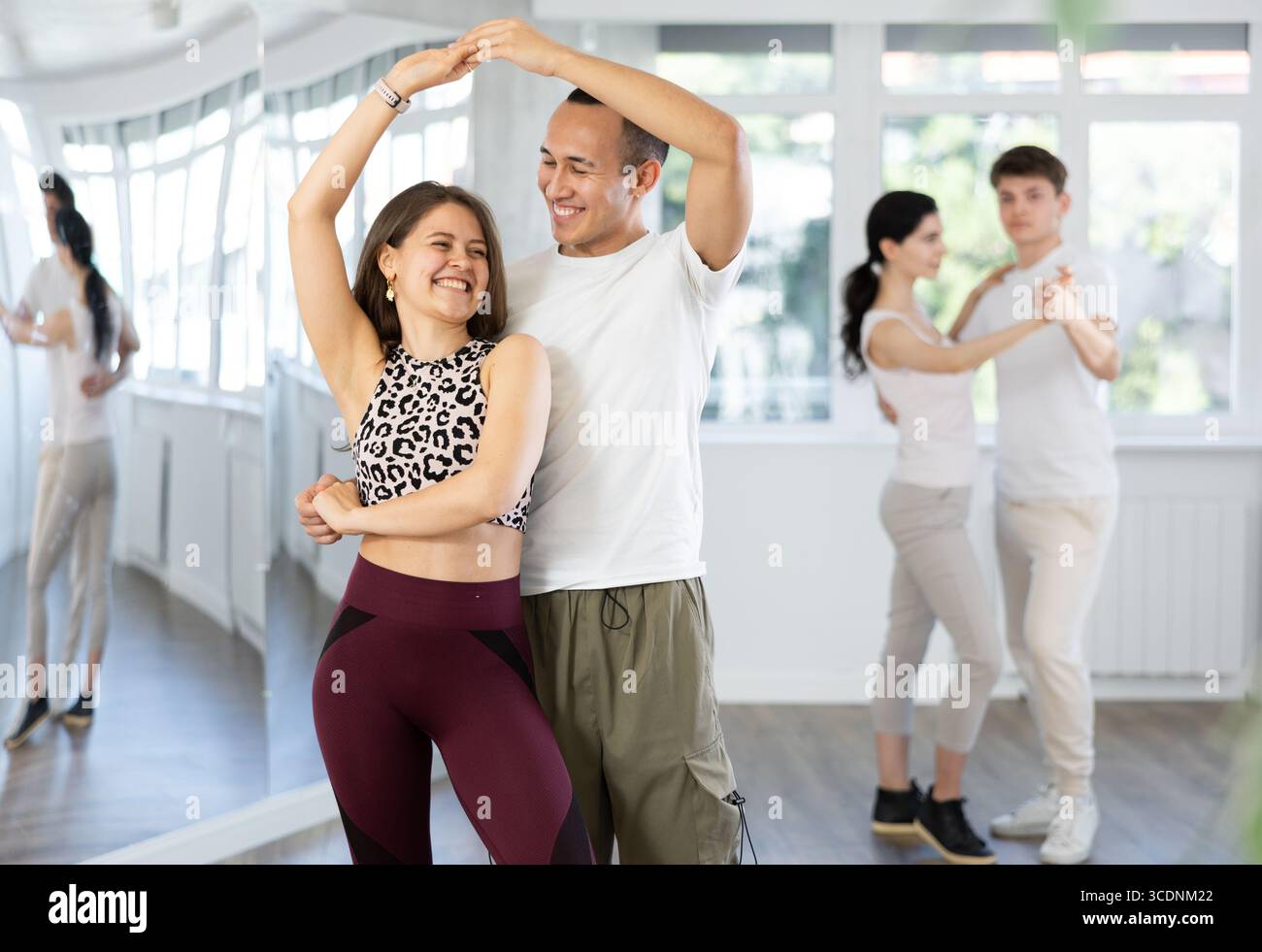 Positive young woman and man practicing waltz dance moves in pair ...
