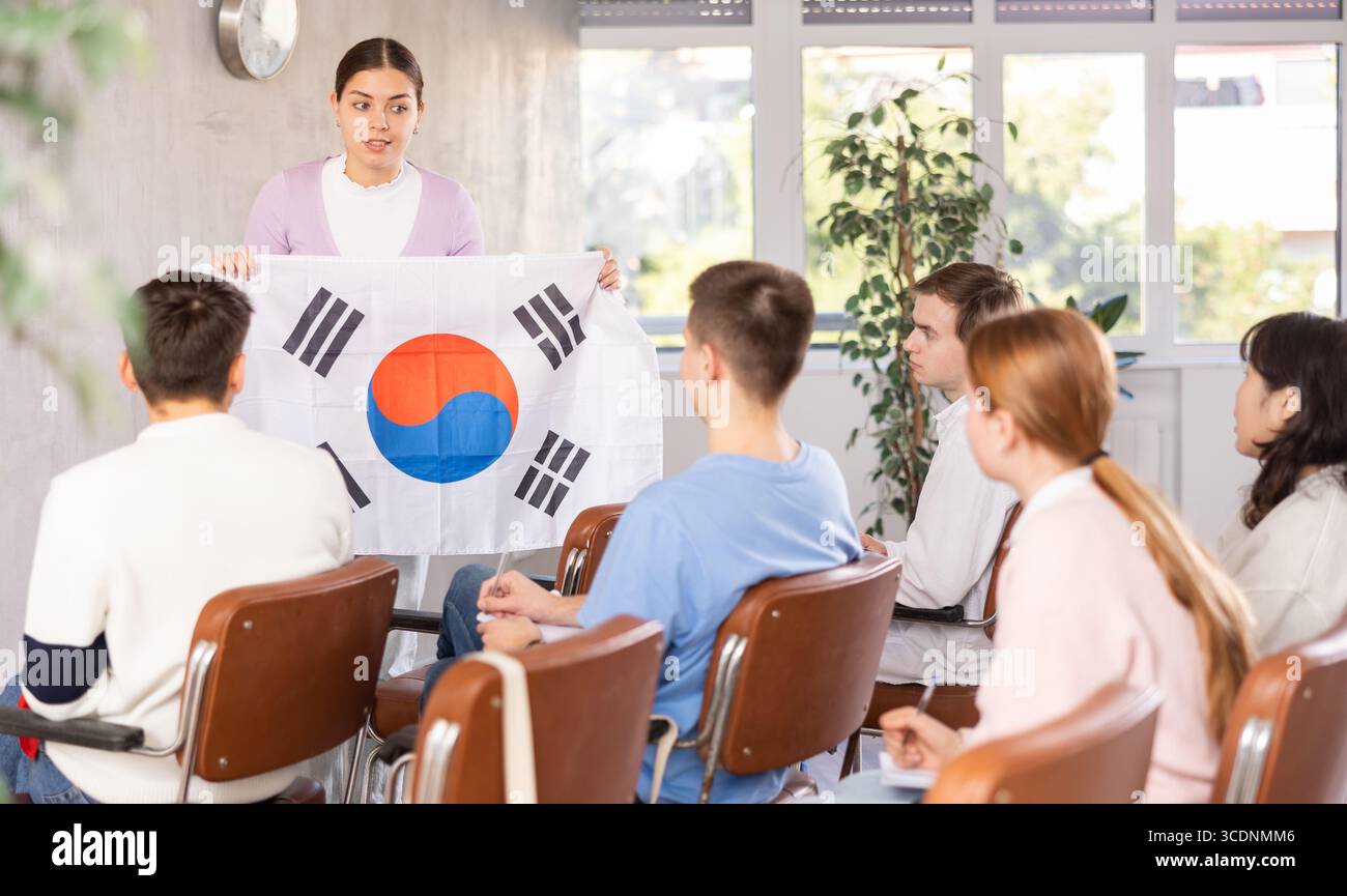 Young woman teacher holding flag of South Korea in front of group of ...