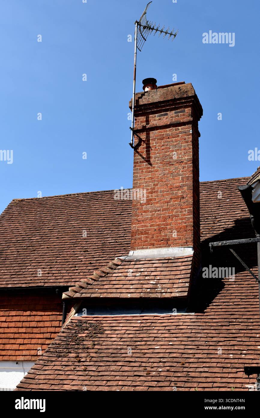 The tiled roof and red bricked chimney of an English country cottage ...